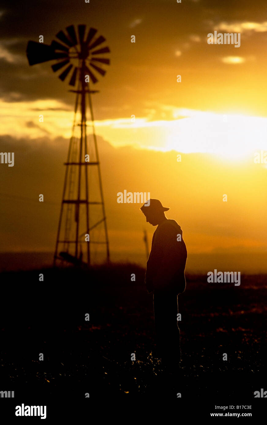 Silhouette of a man standing in front of a rural windmill Stock Photo ...