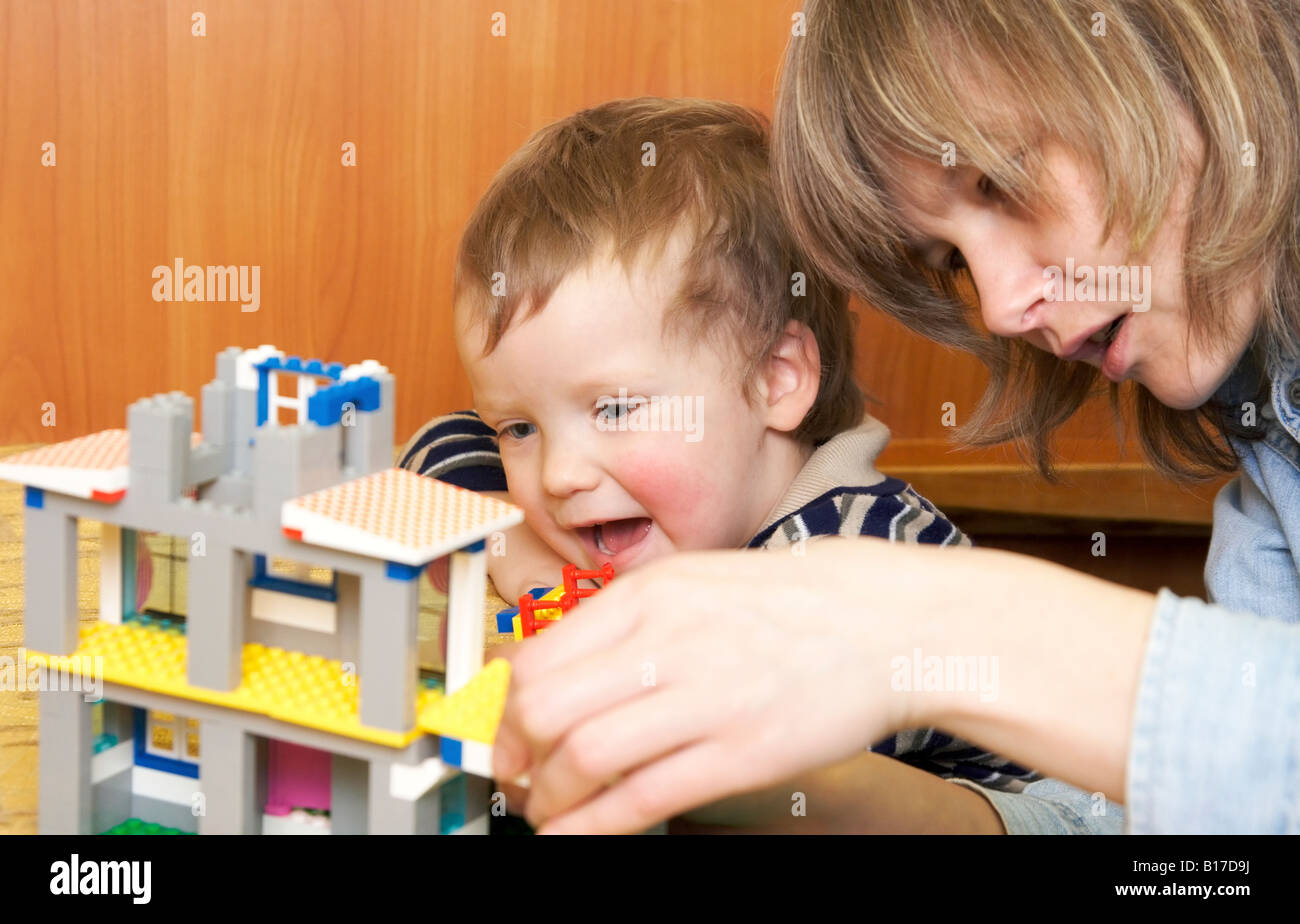 Mother with small son play with building set for children (built a ...