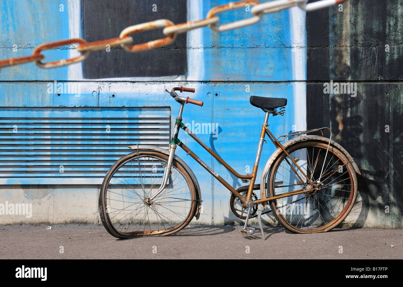 Old and broken bicycle left alone in front of a blue wall Stock Photo ...