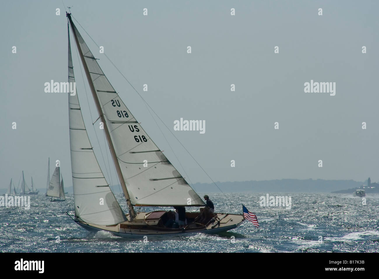Photo of a classic sail boat sailing in open water with land, sailboats ...
