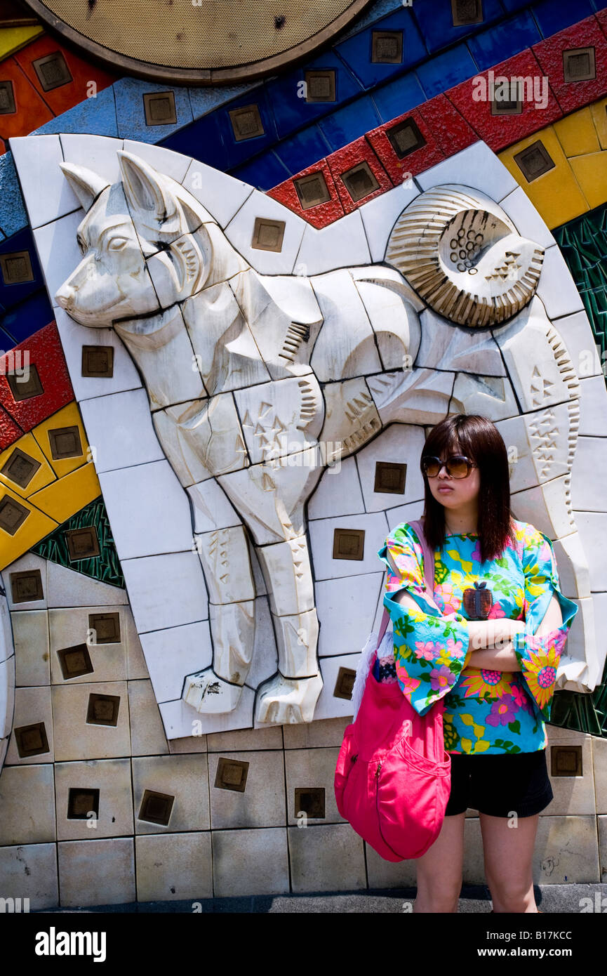 Girl waiting for friend below stone mural of Hachiko the Dog outside ...