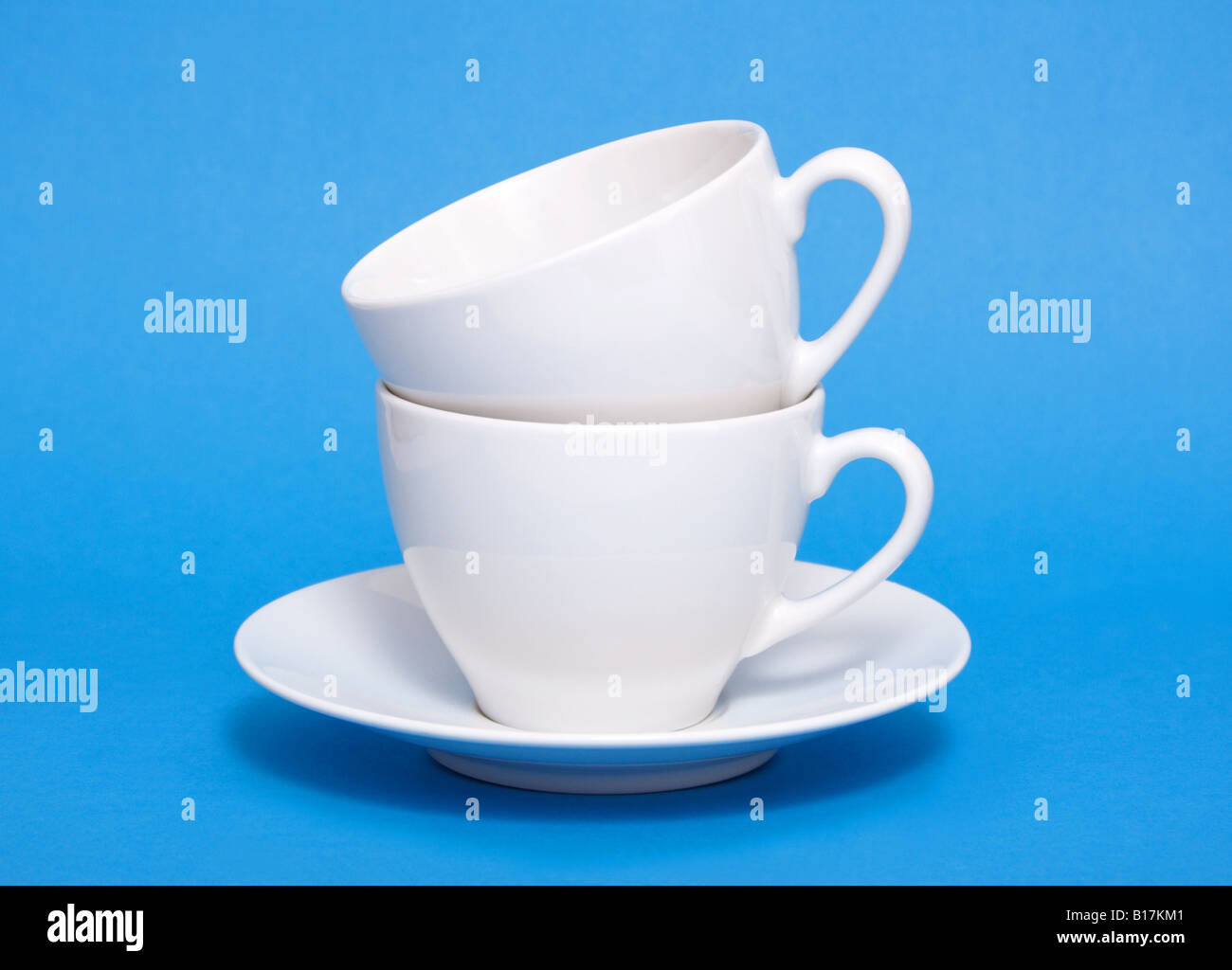 Two white coffee cup piled on blue background Stock Photo - Alamy