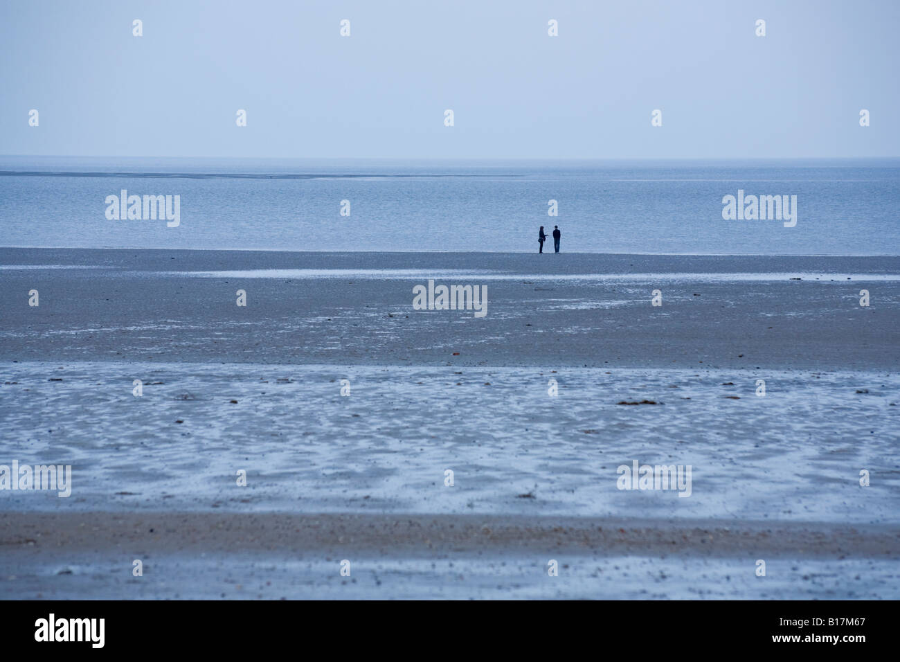 Couple silhouette on the beach at low tide. Monotone cool blue. Generic ...