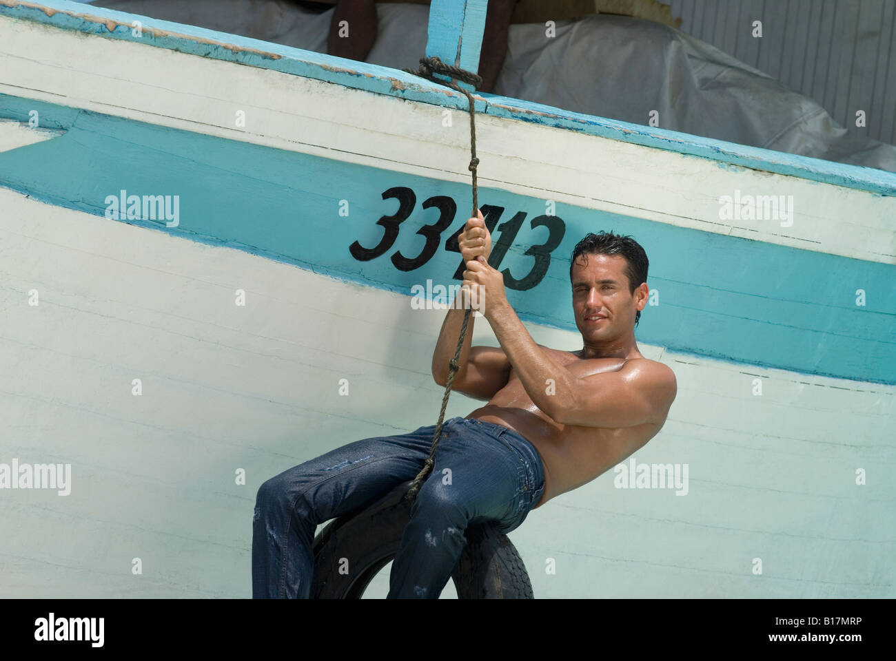 Hispanic man in tire swing on boat Stock Photo - Alamy