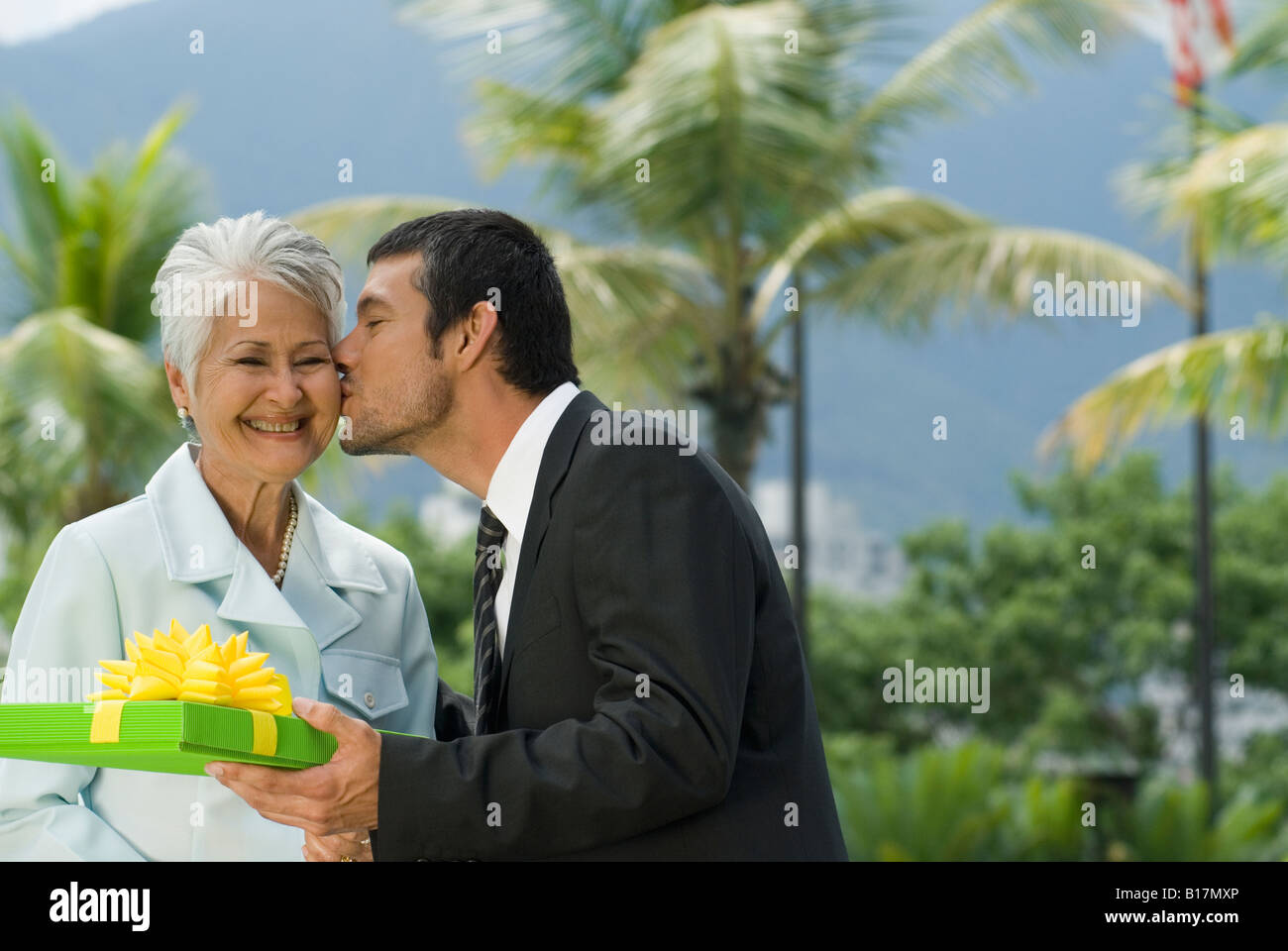 Hispanic man giving gift to mother Stock Photo - Alamy