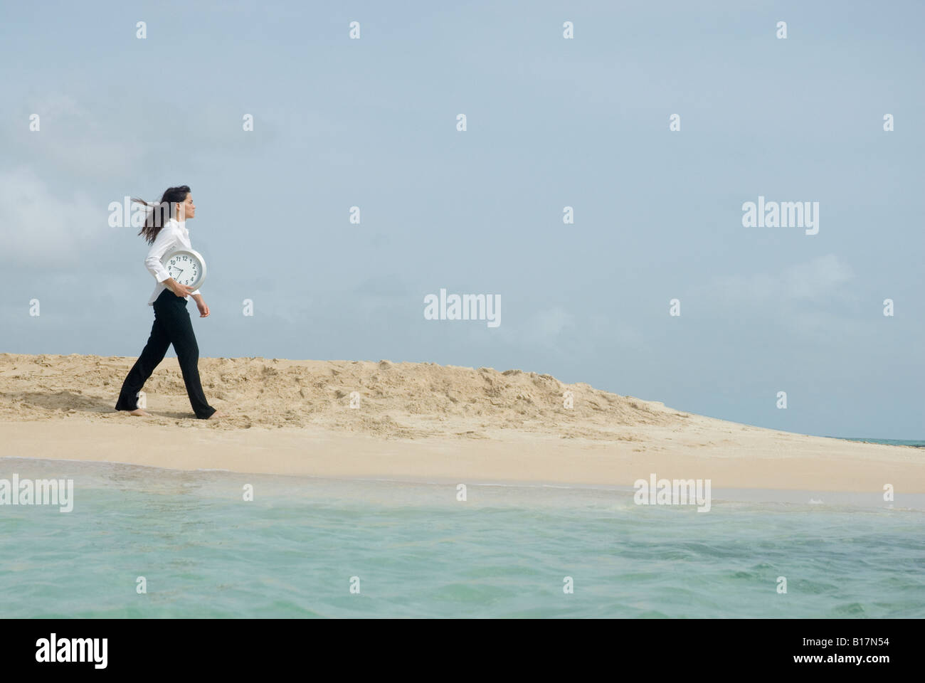 Woman carrying clock at beach Stock Photo - Alamy