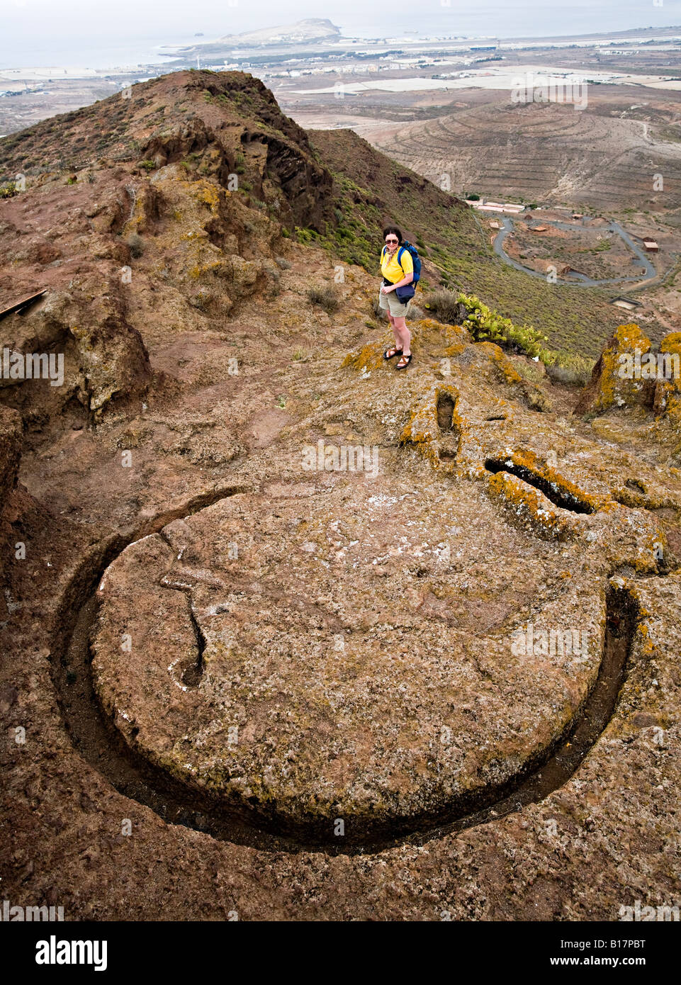 Female visitor looking at incised channels in the rock near Cuevas de ...