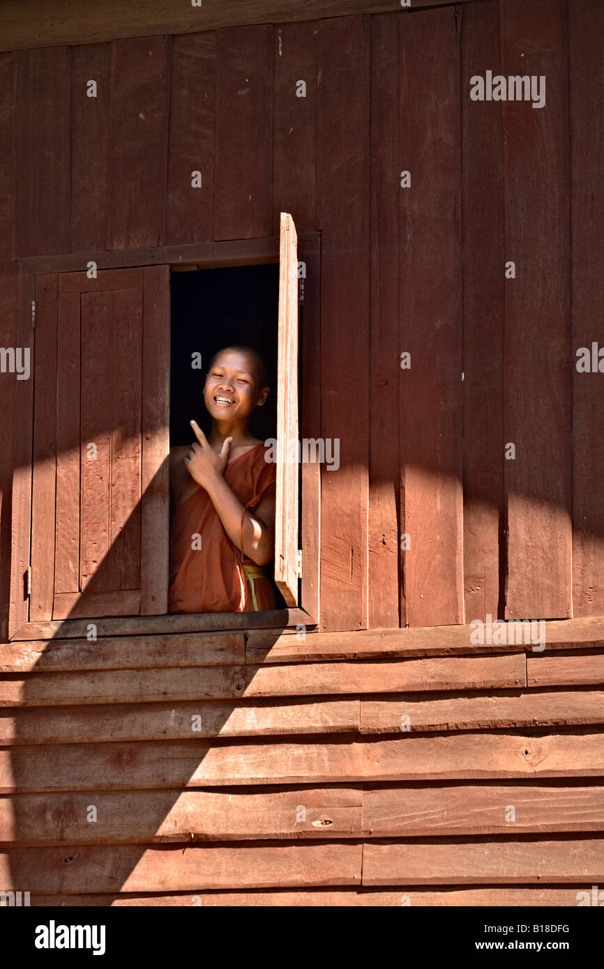 Young Buddhist monk signals greeting from dorm window, southern Laos ...
