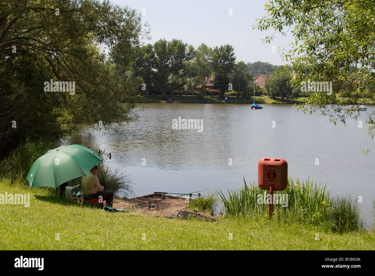 One man fishing in the lake at Goldsworth Park Woking Surrey England ...