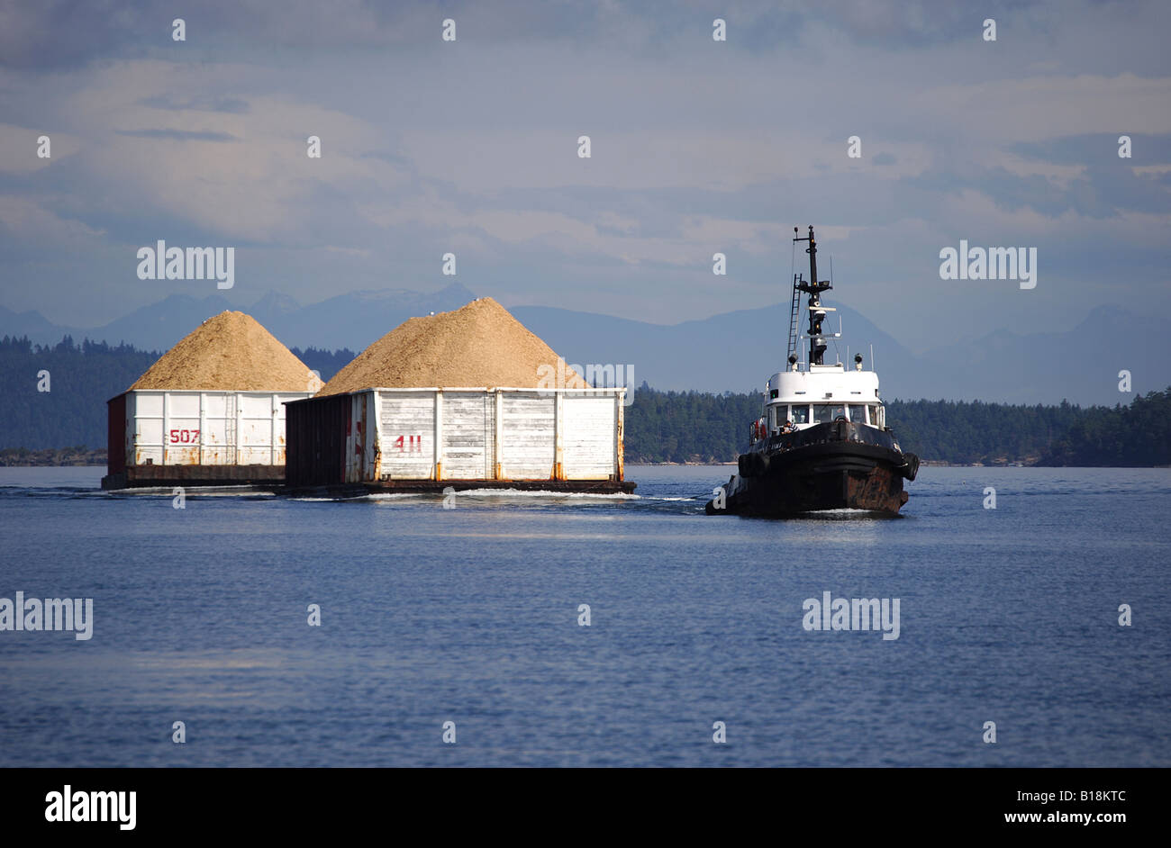 A tug pulls barges of wood chips through Stuart Channel near Kuper and ...