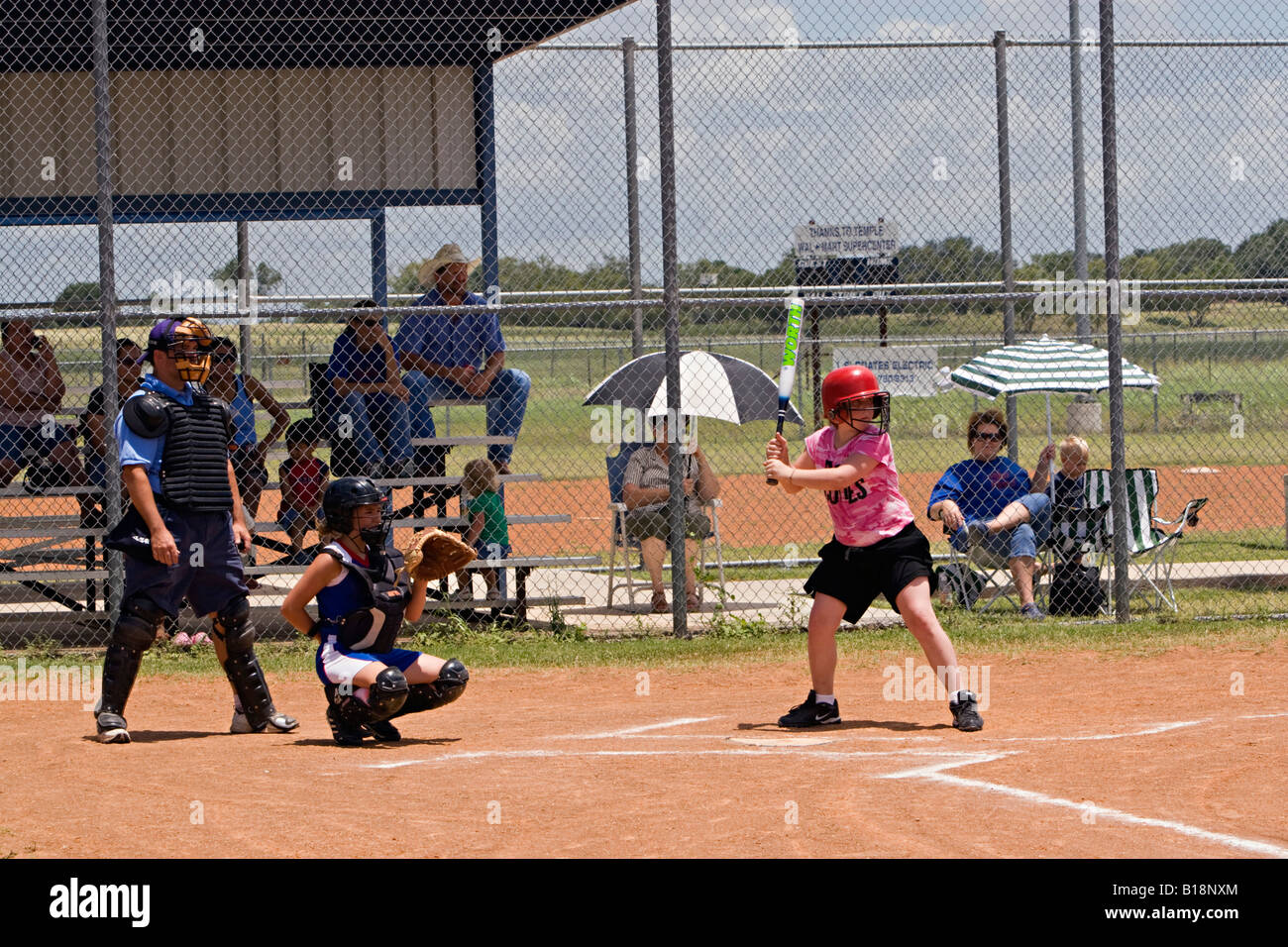 Girls youth softball team batter at home plate waiting on pitch of ball ...