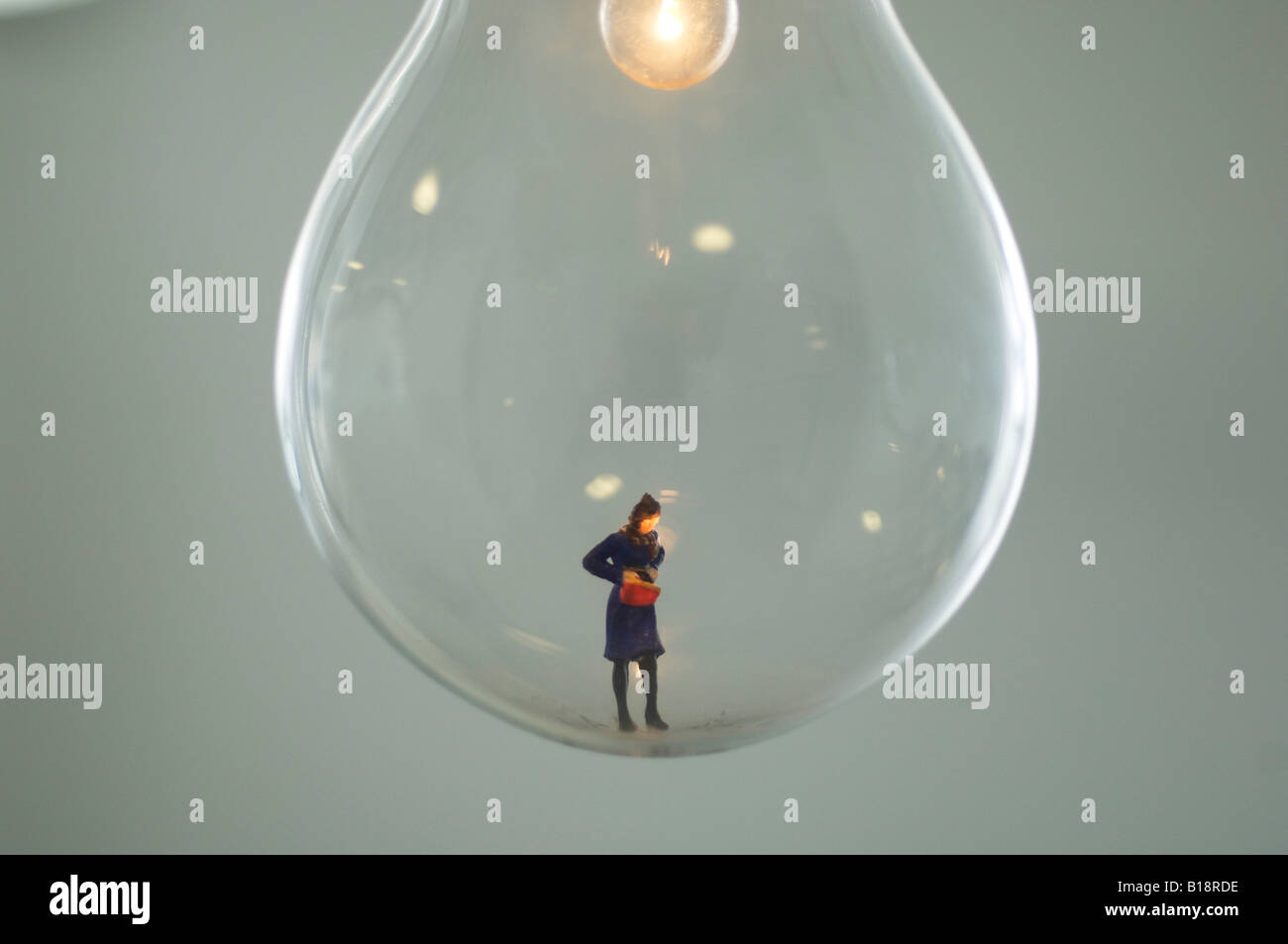 A tiny sculpted figure alone inside a light-bulb with a light ...