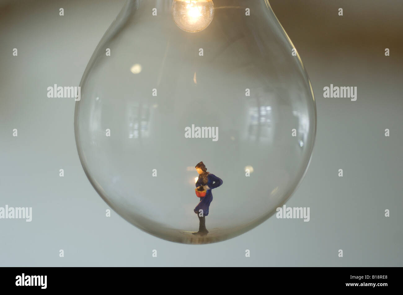 A tiny sculpted figure alone inside a light-bulb with a light ...