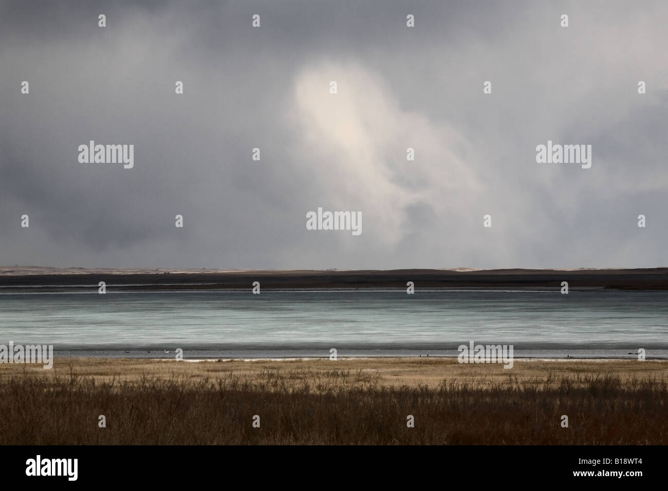 Storm clouds over frozen slough in early spring Stock Photo - Alamy