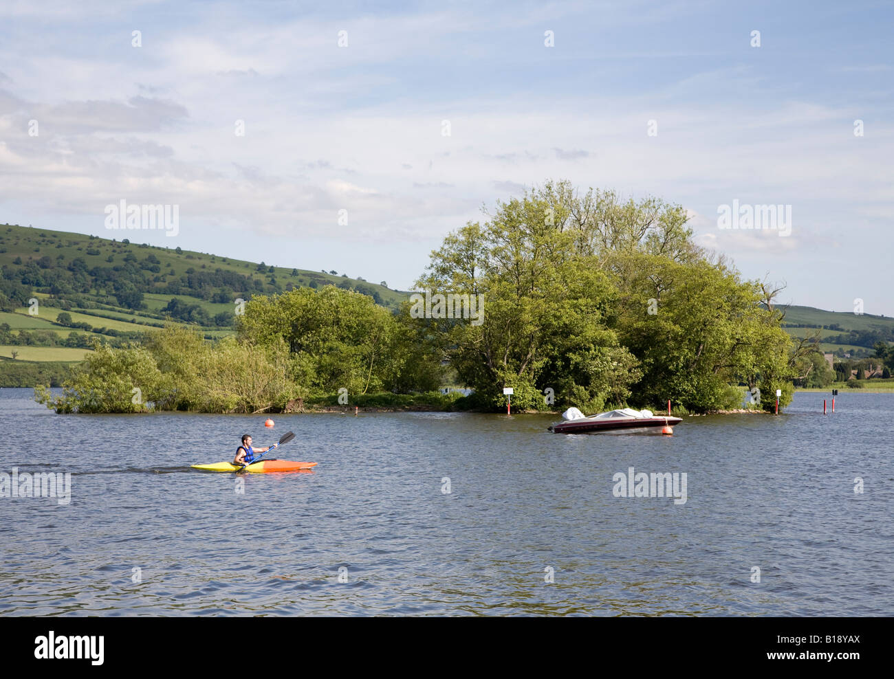 Man kayaking past the crannog or man made island in Llangorse Lake ...