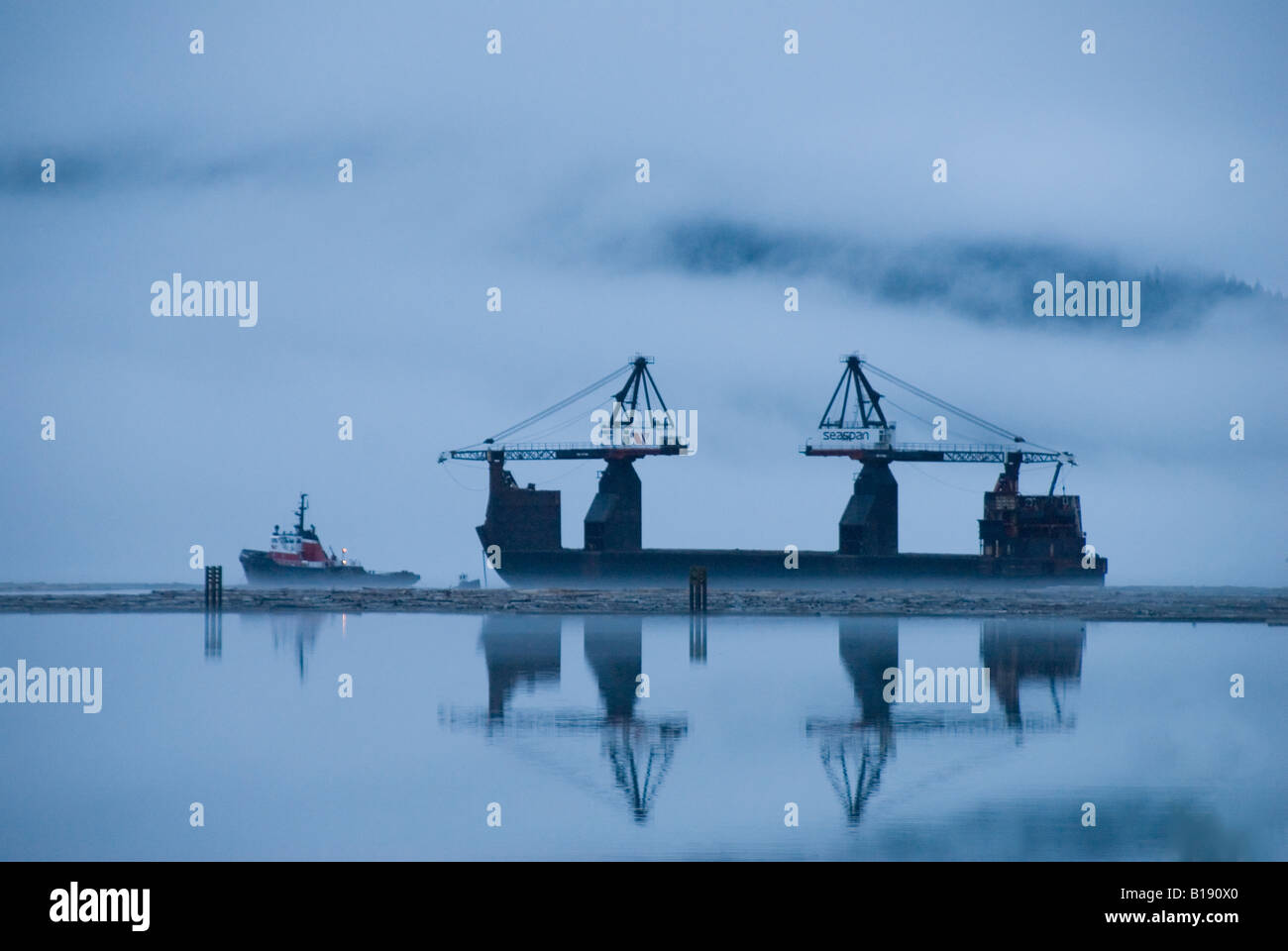 Log Barge. Cranes lift and pile the logs on the deck surface. Once ...