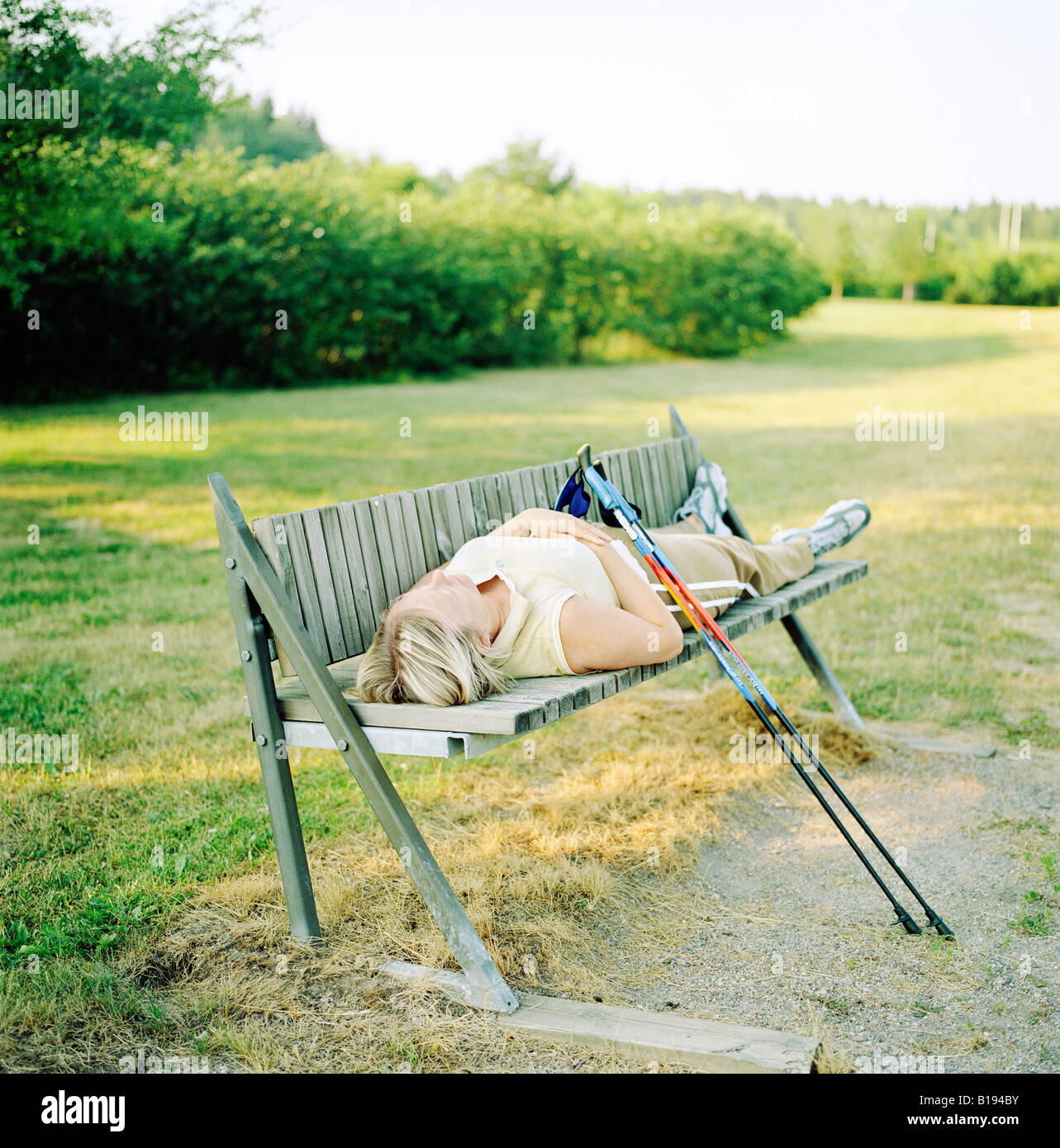 Mature woman lying on a bench Stock Photo - Alamy