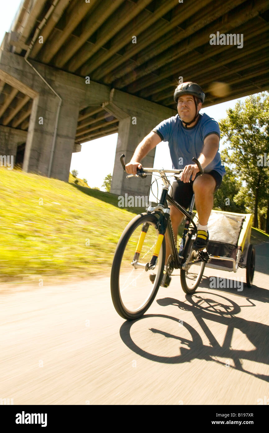 Man riding bicycle under overpass with cart behind, Lachine, Quebec ...