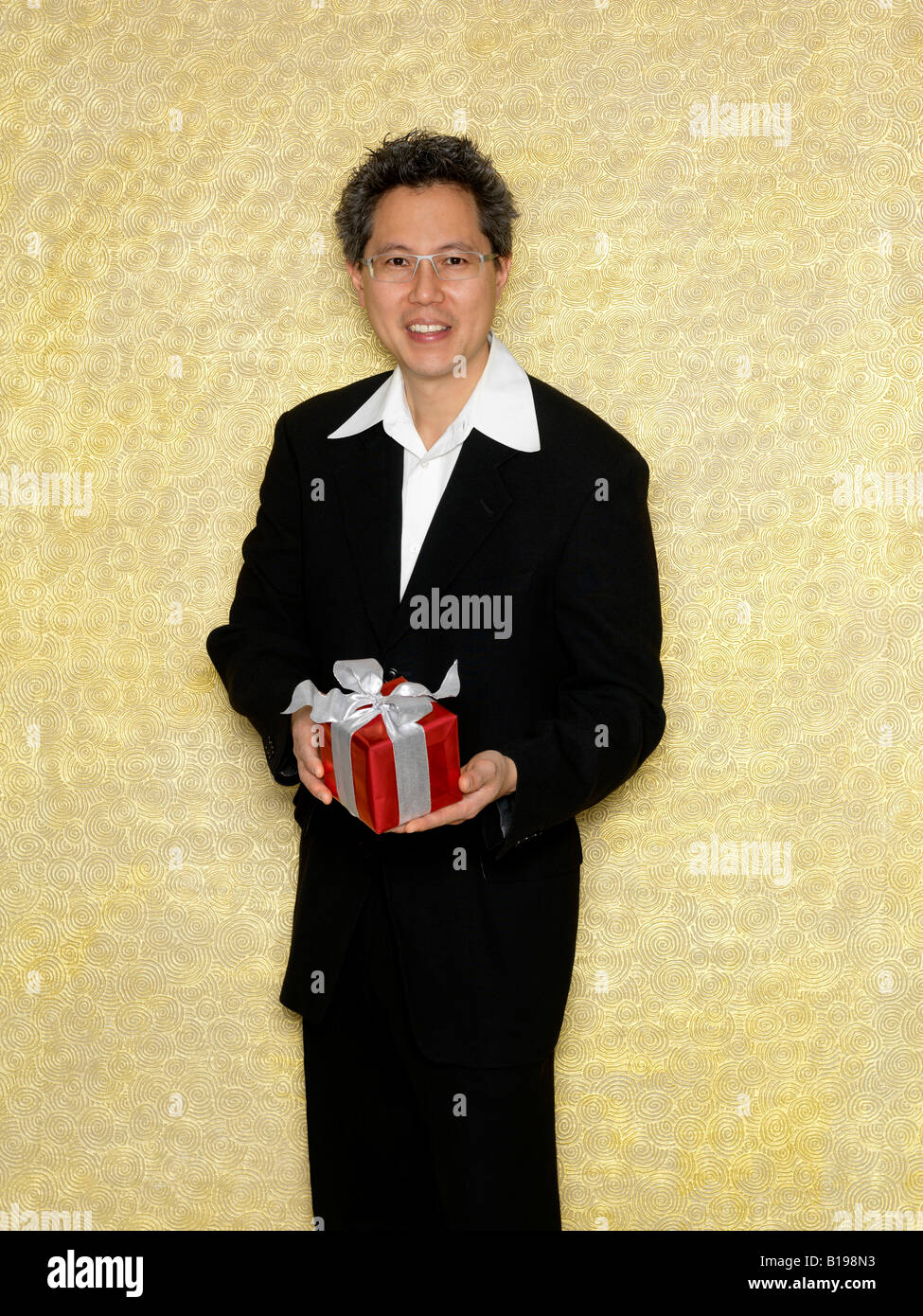 43 year old asian male holding a gift against a gold background Stock ...