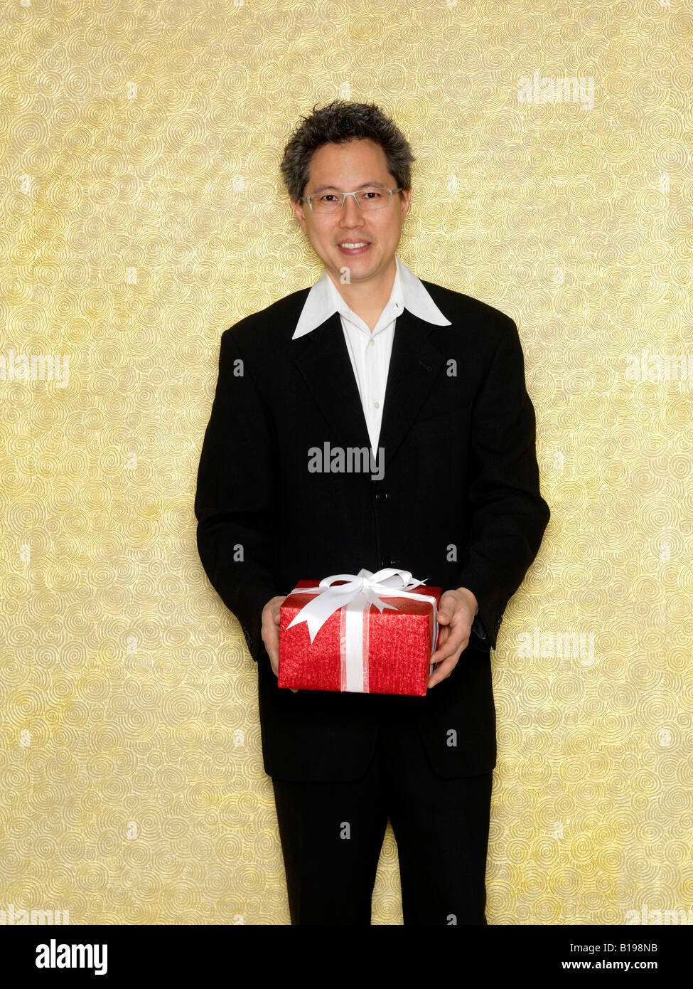 43 year old asian male holding a gift against a gold background Stock ...