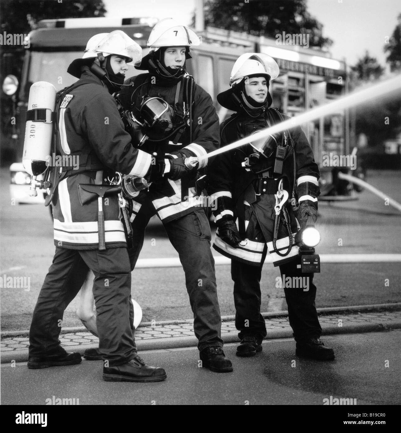 young firefighters with breathing protection and extinguisher in action ...