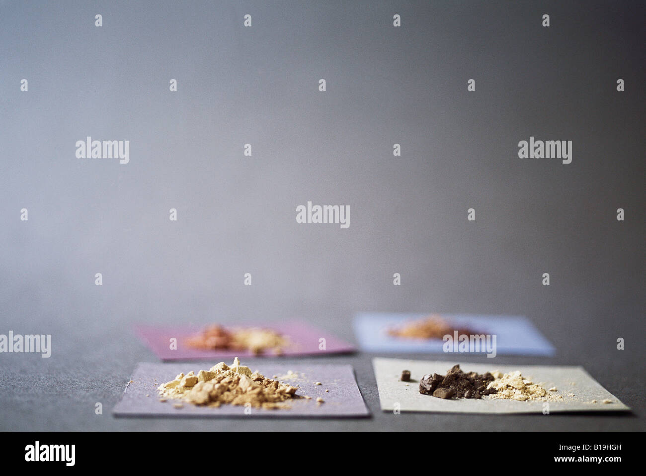 Four squares of paper holding different colored powders Stock Photo - Alamy