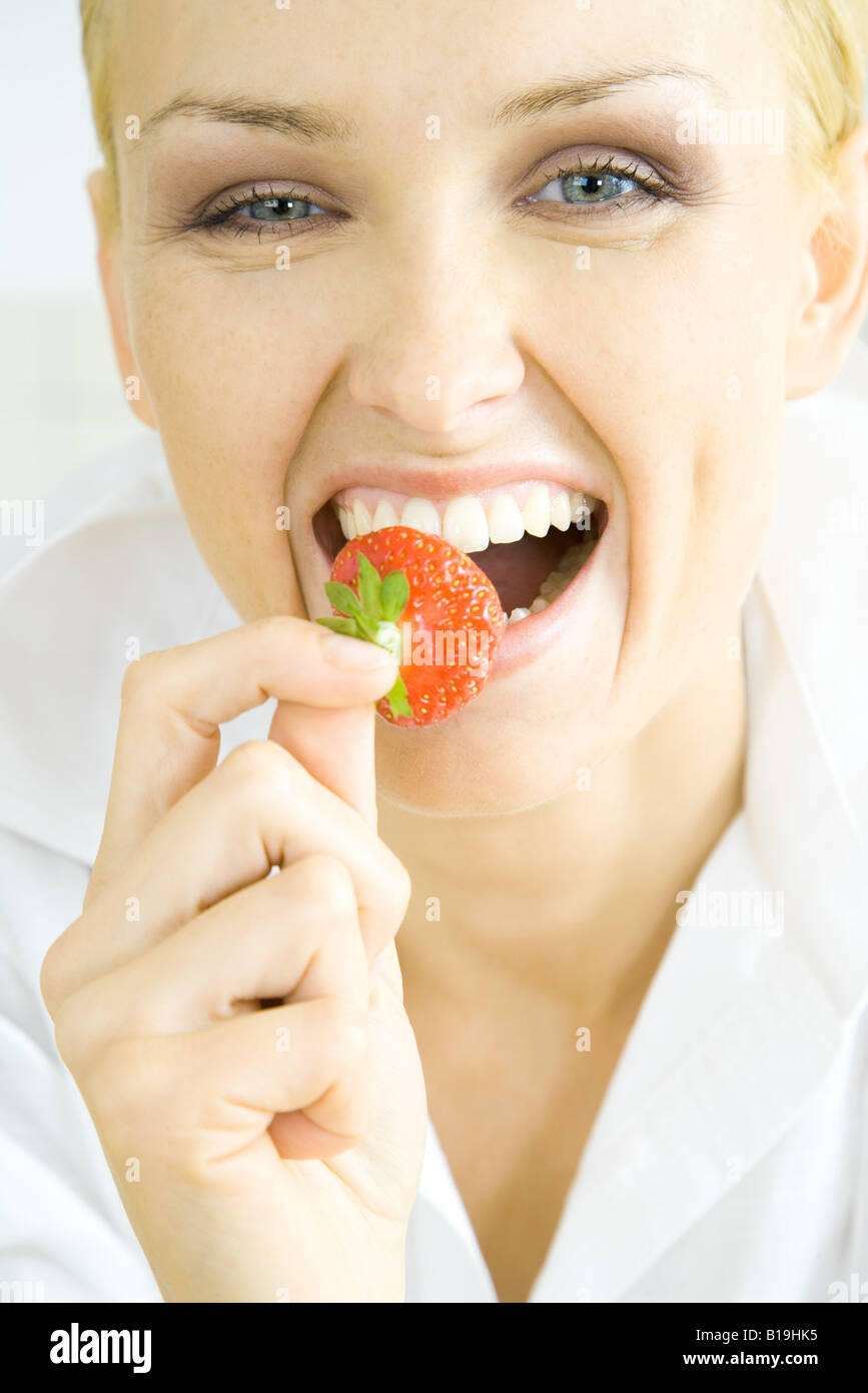 Woman biting into strawberry Stock Photo - Alamy