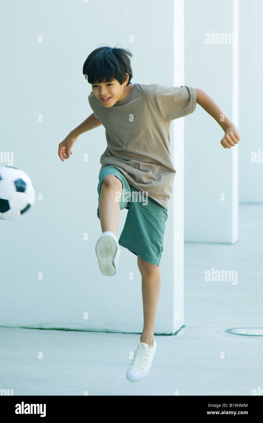 Boy kicking soccer ball, full length Stock Photo - Alamy