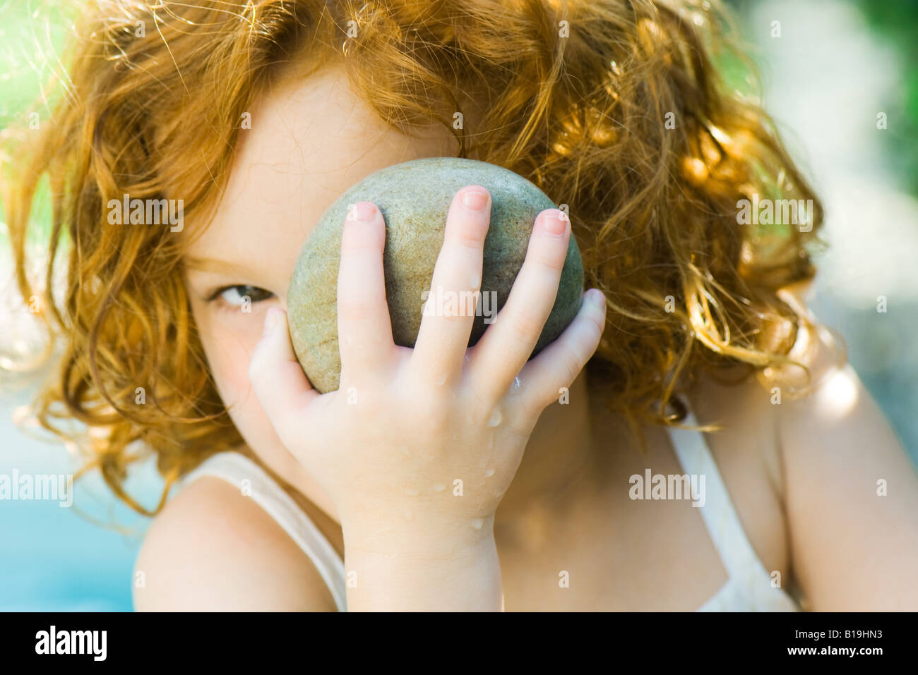 Girl holding up stone to face Stock Photo - Alamy