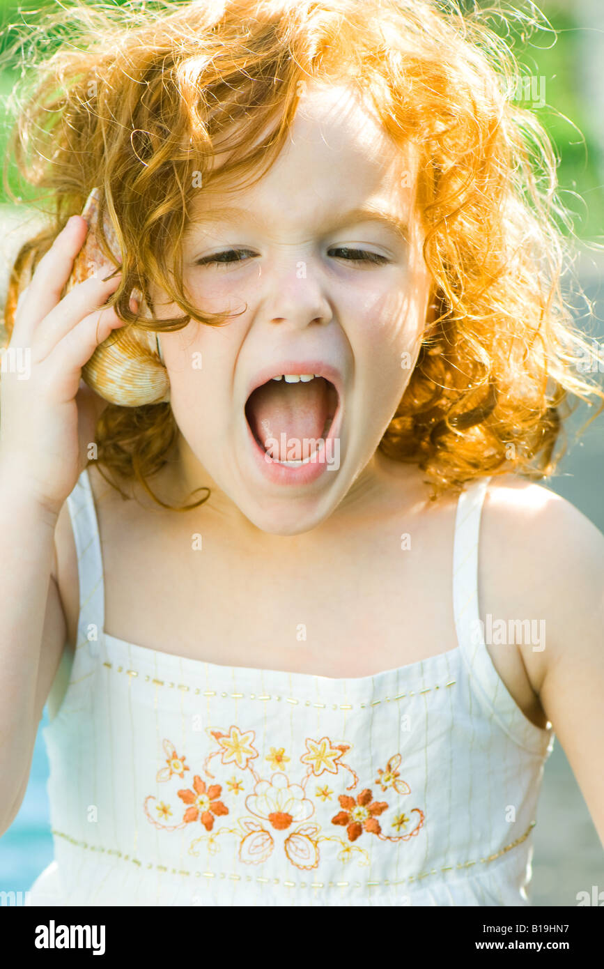 Girl listening to seashell, shouting Stock Photo - Alamy
