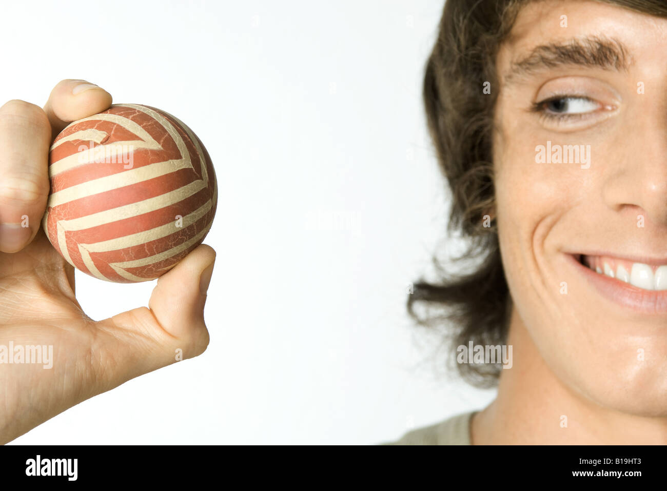 Young man holding ball, smiling, cropped view Stock Photo - Alamy