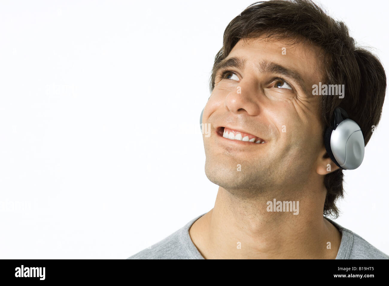 Man listening to headphones, looking up, smiling Stock Photo - Alamy