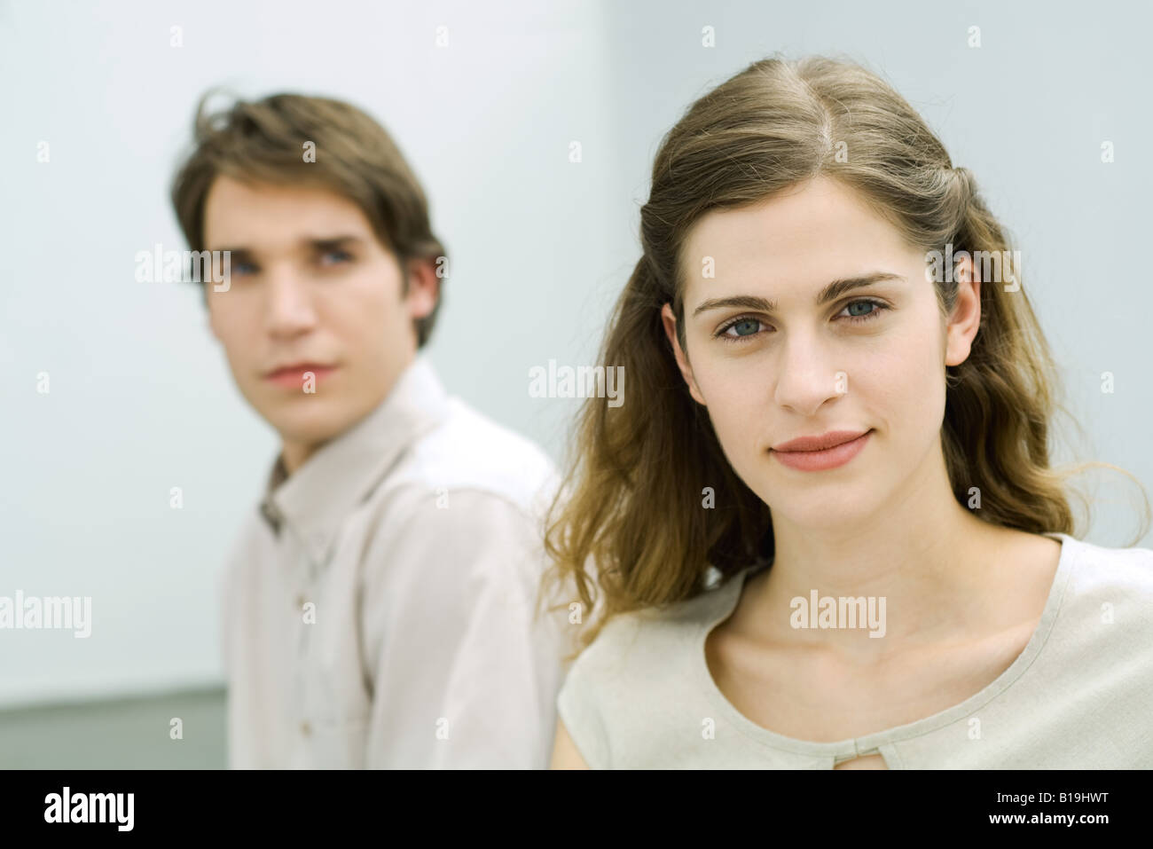 Woman smiling at camera, man behind, looking at woman Stock Photo - Alamy
