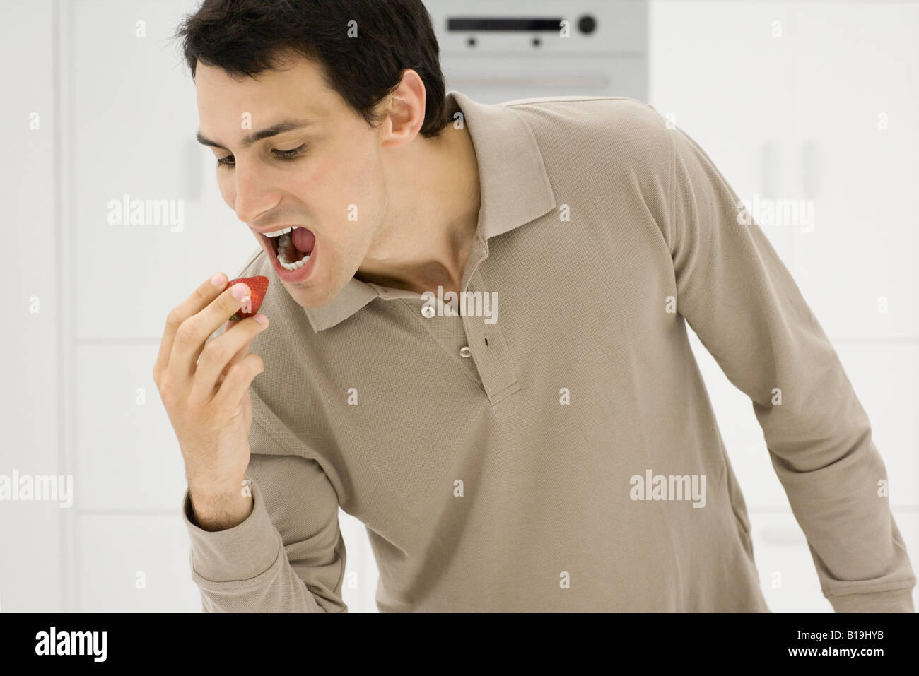Man eating strawberry, mouth open Stock Photo - Alamy