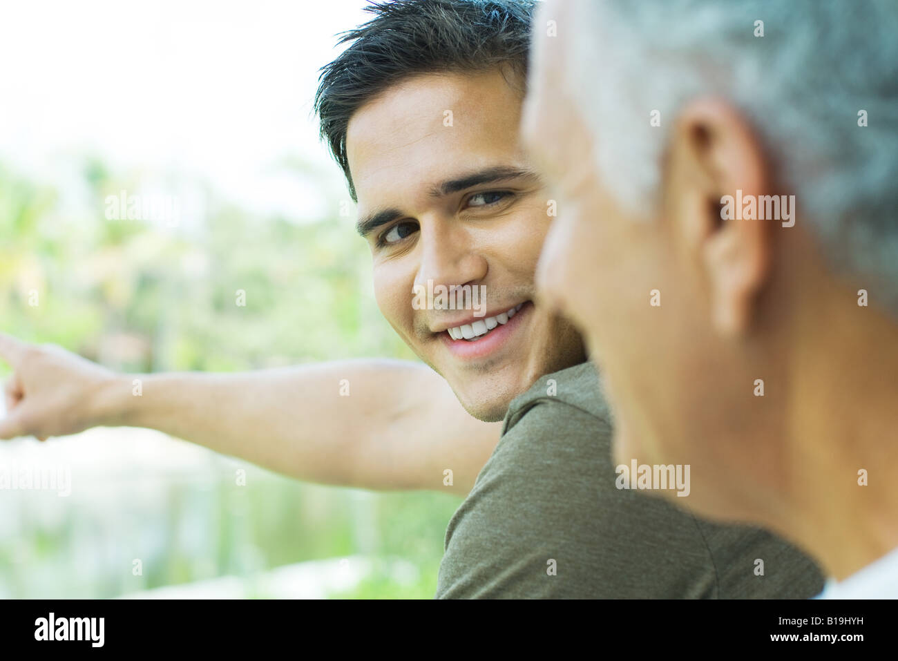 Young man pointing, looking over shoulder at father, cropped view Stock ...