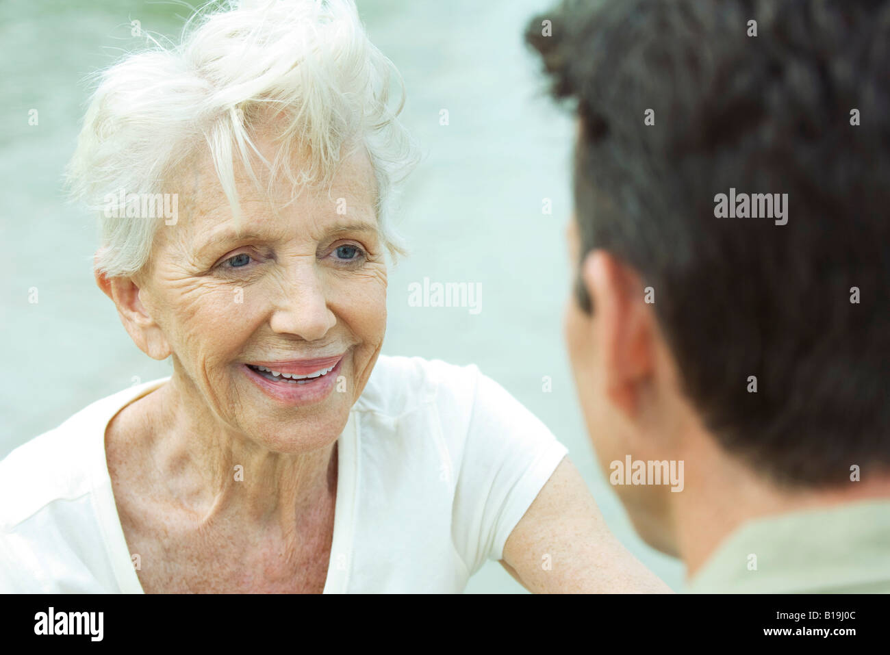 Senior woman smiling at man, over the shoulder view Stock Photo - Alamy