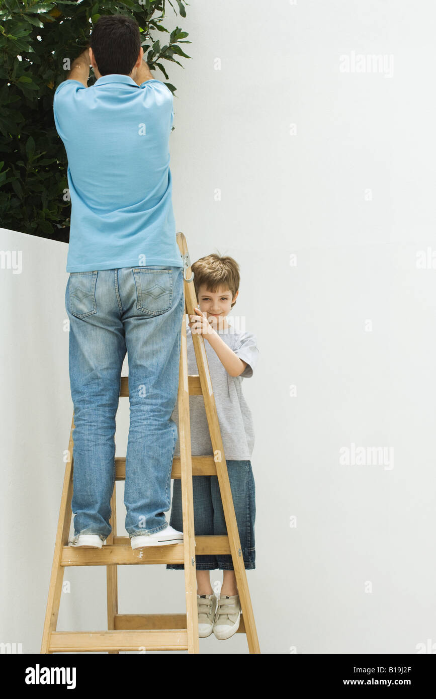 Father and son standing on ladder together, boy smiling at camera Stock ...