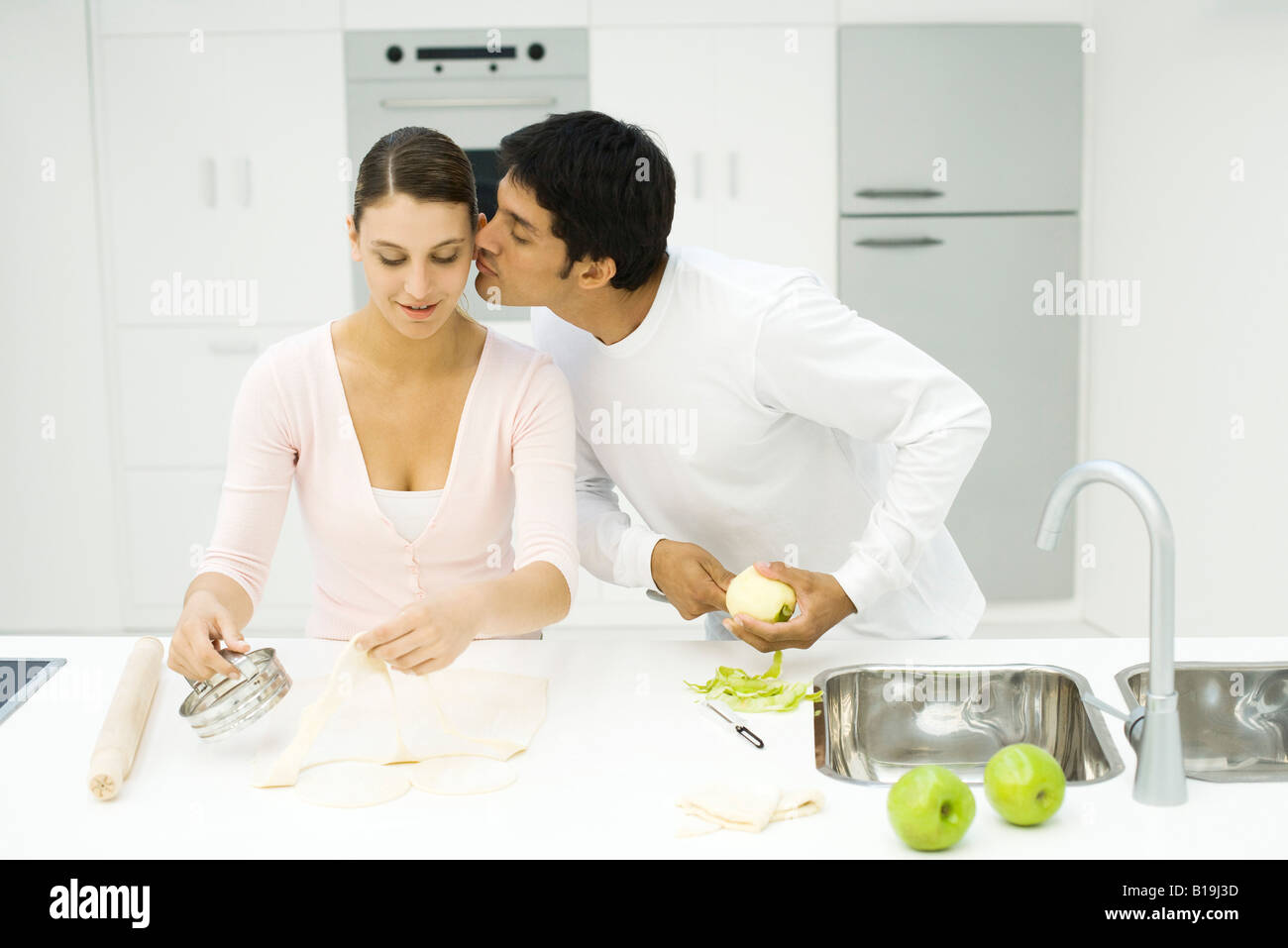 Couple cooking together, man kissing woman's cheek Stock Photo - Alamy