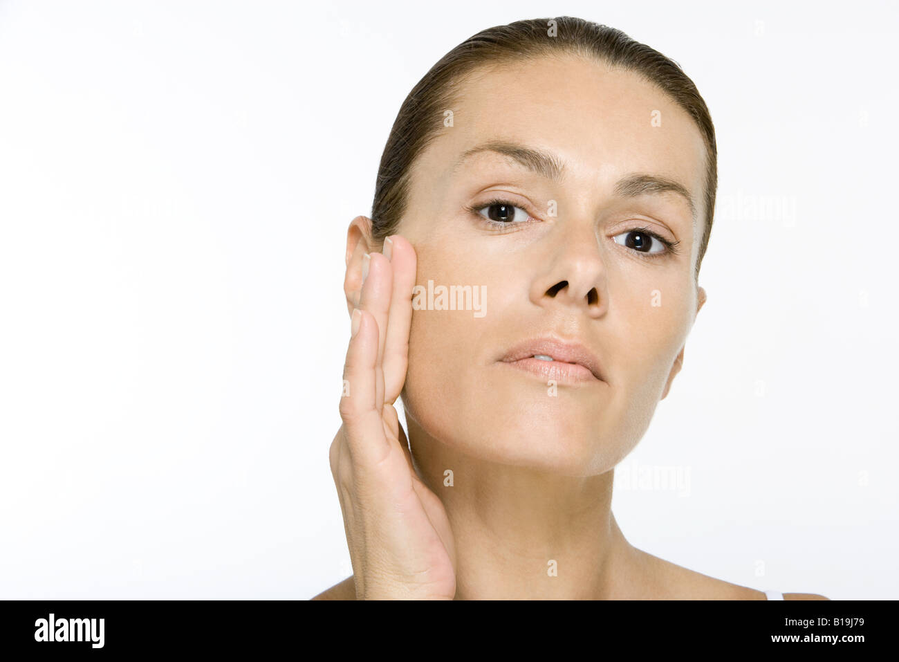 Woman touching cheek, looking at camera Stock Photo - Alamy