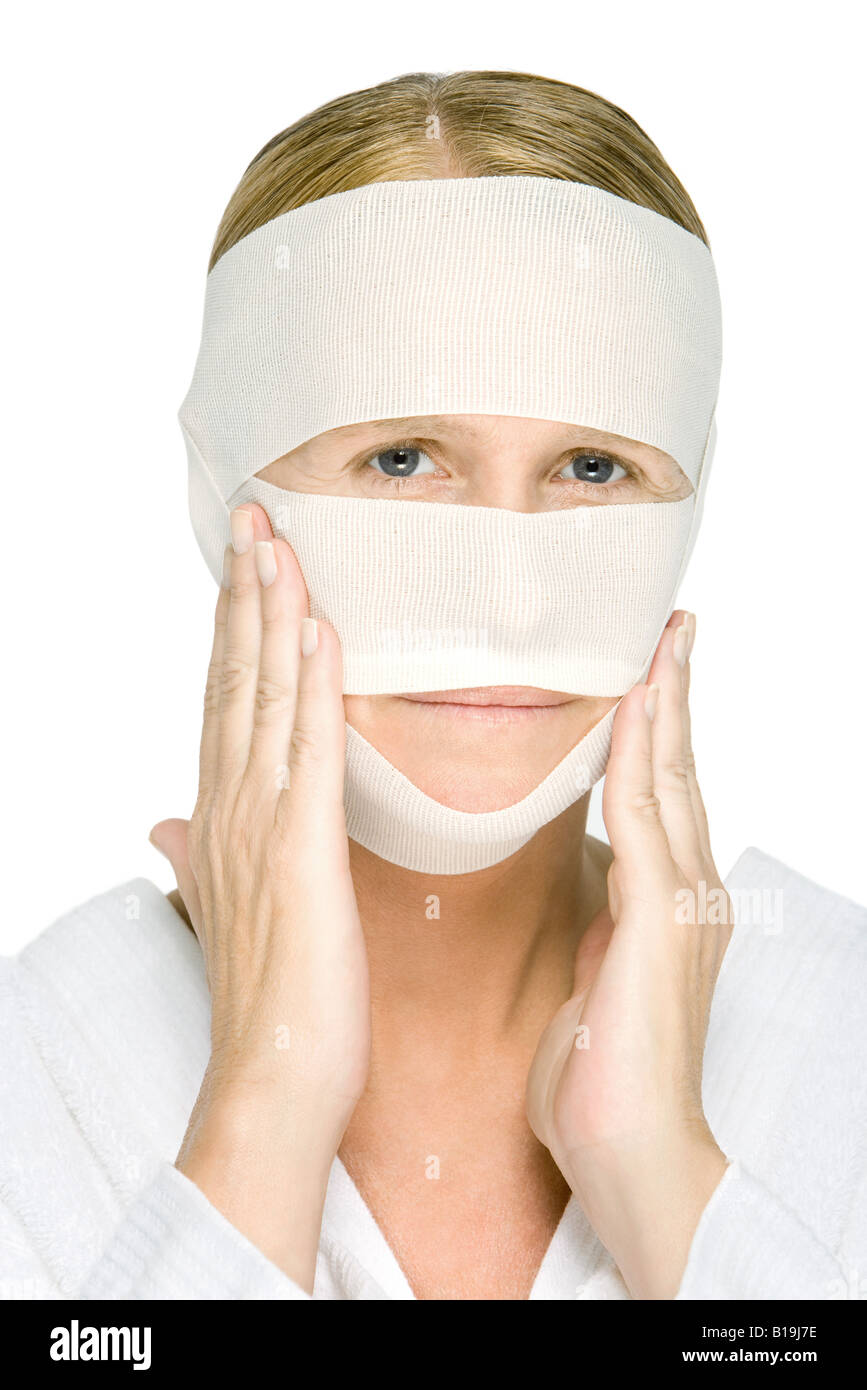 Woman with bandaged face, touching cheeks, looking at camera Stock ...