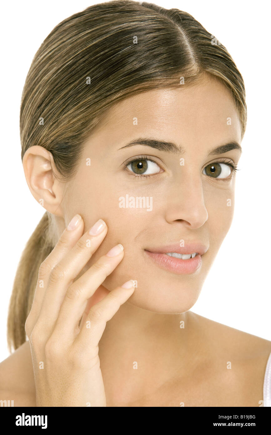Woman touching cheek, smiling at camera, portrait Stock Photo - Alamy
