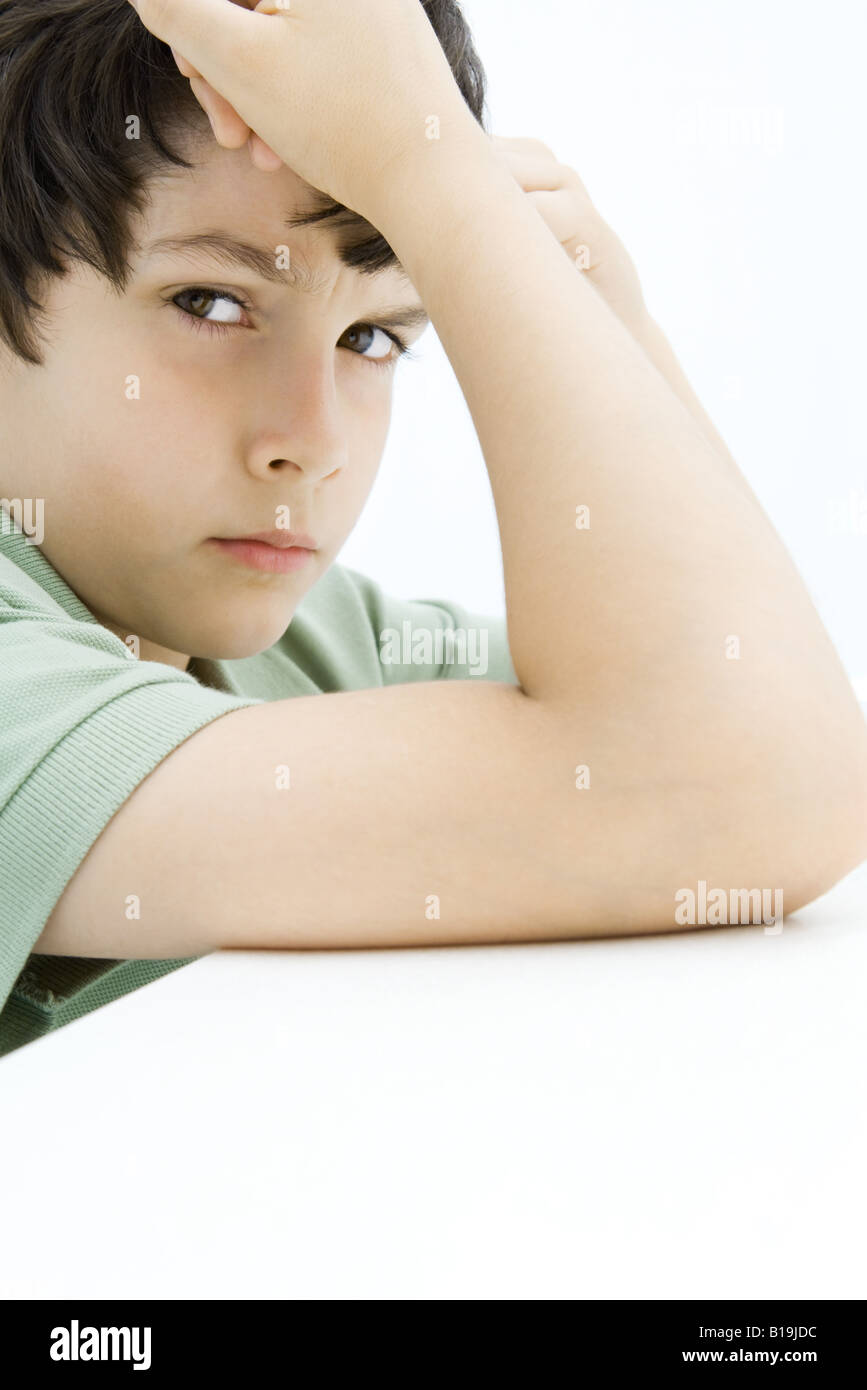 Boy frowning at camera, holding head, leaning on elbow Stock Photo - Alamy