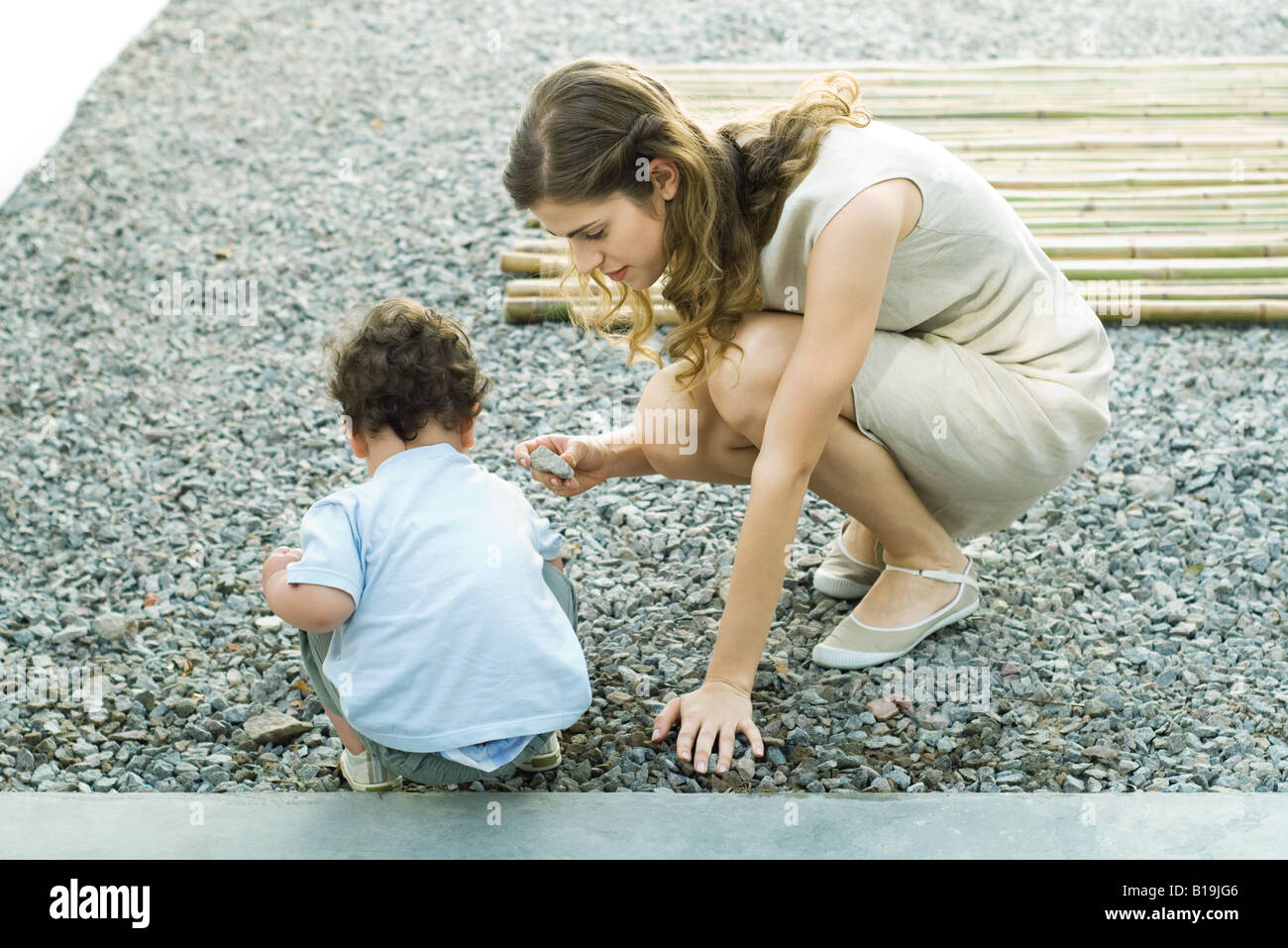 Mother and toddler crouching on gravel, looking at rocks Stock Photo ...