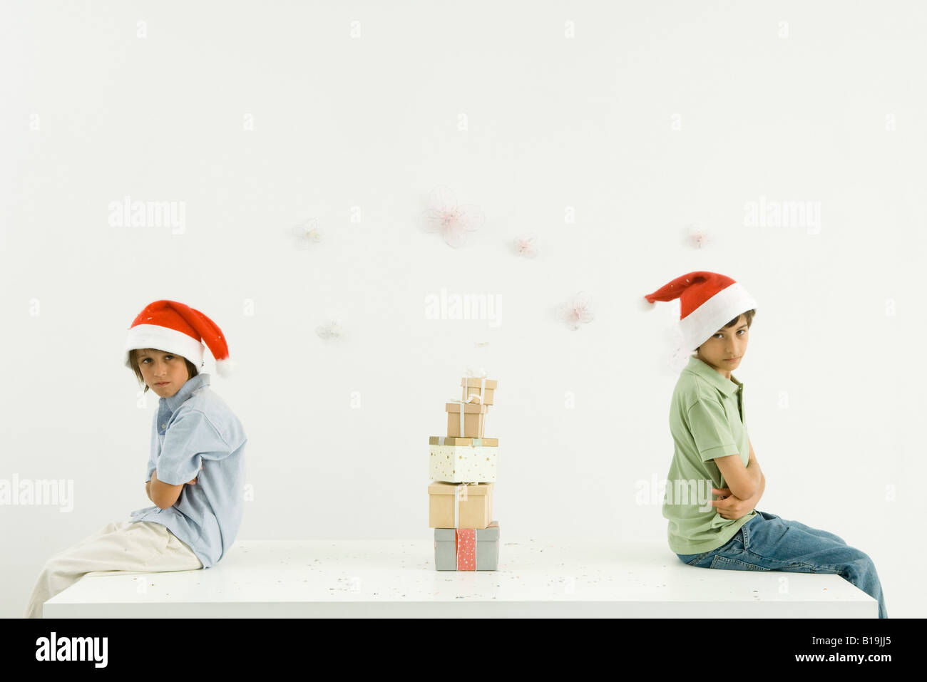 Two brothers sitting back to back with arms folded, Christmas gifts ...