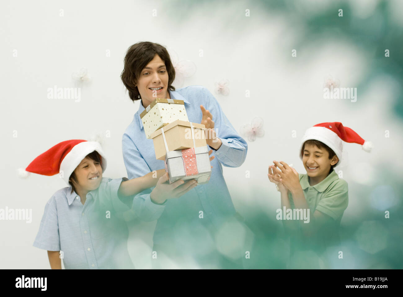 Boy knocking over stack of Christmas gifts in his older brother's arms ...