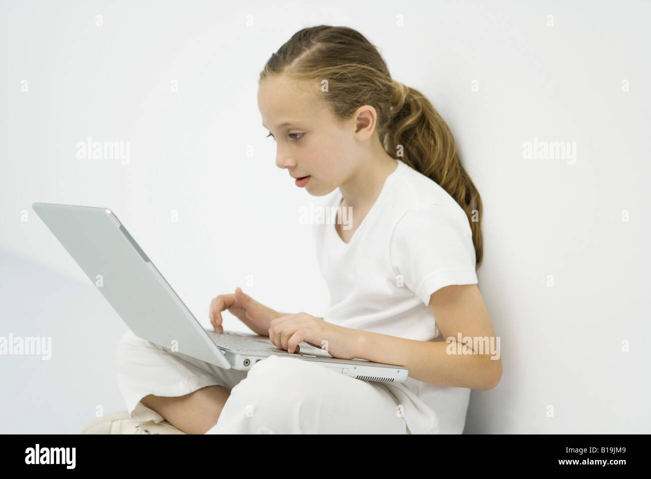Little girl using laptop computer, side view Stock Photo - Alamy