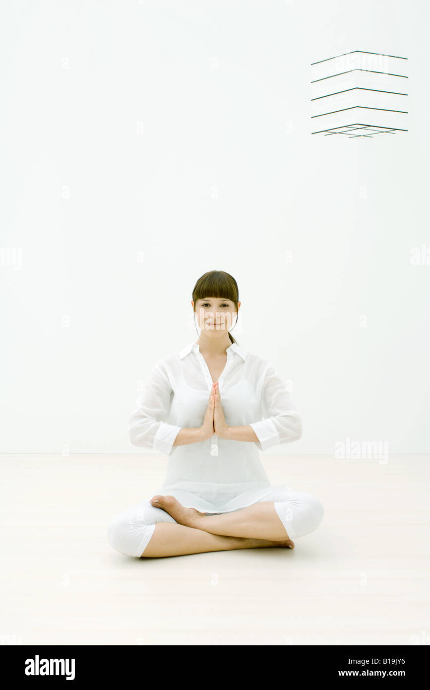 Woman sitting in lotus position on floor, smiling at camera Stock Photo ...
