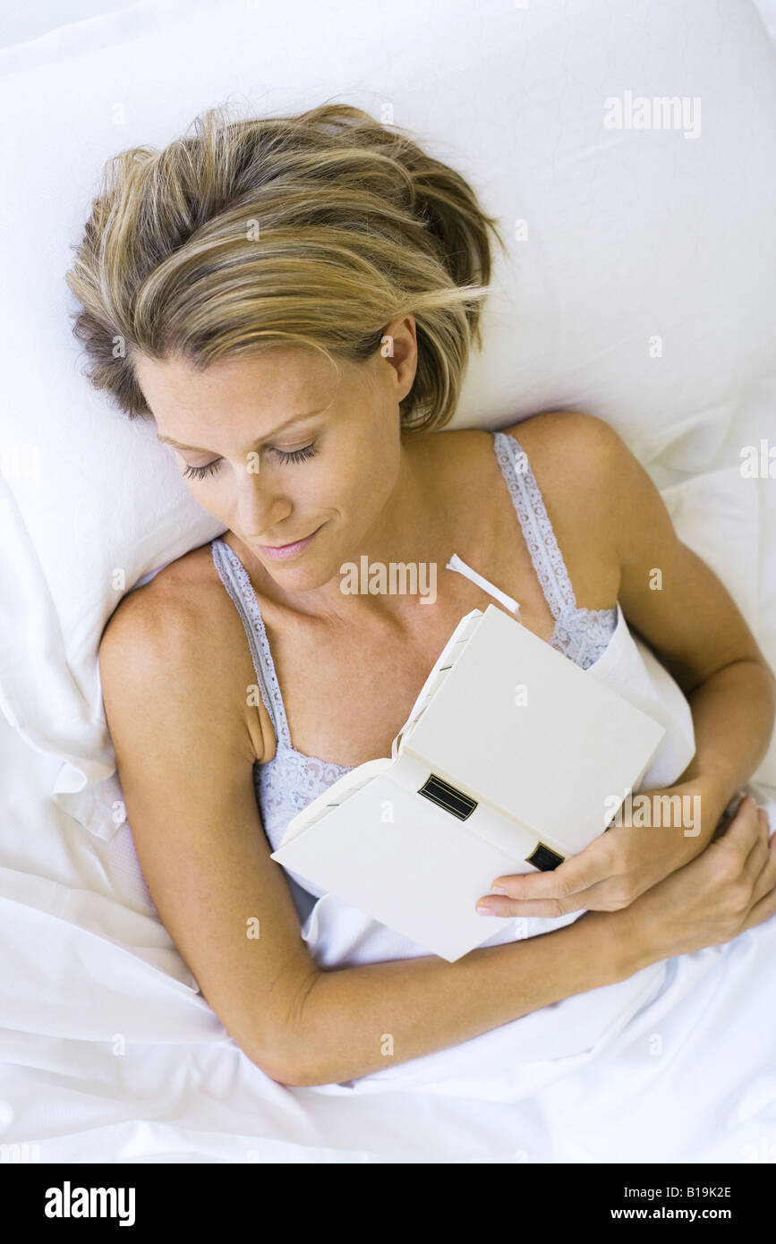 Woman asleep in bed, holding book against chest Stock Photo - Alamy