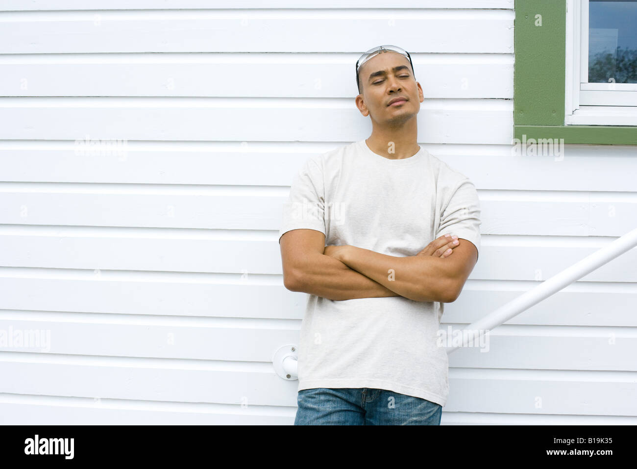 Man leaning against house with arms folded Stock Photo - Alamy