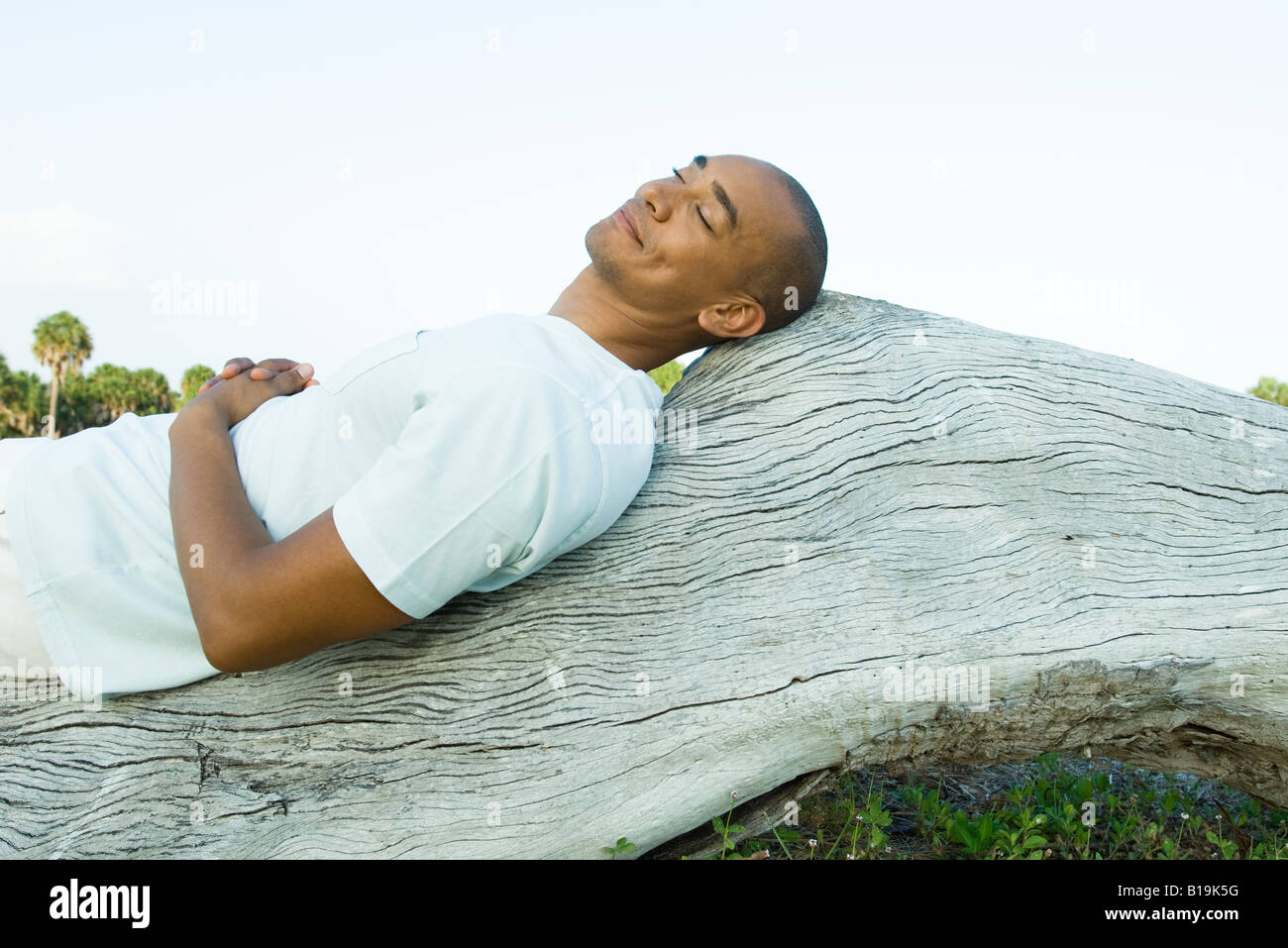 Man lying on back on wood surface, eyes closed, smiling Stock Photo - Alamy
